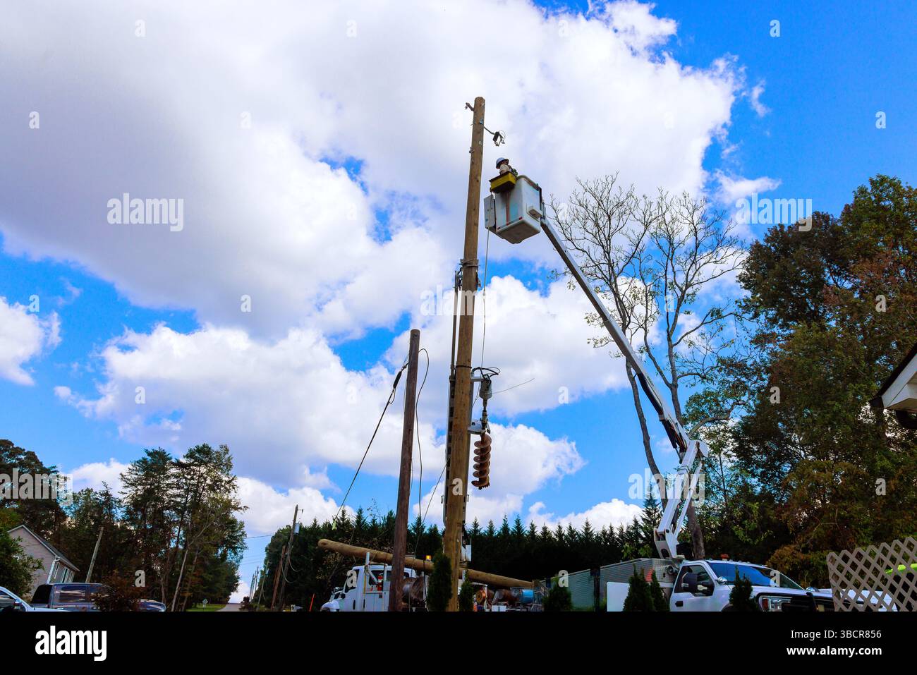 Utility workers use lift trucks to repair power lines while ensuring ...