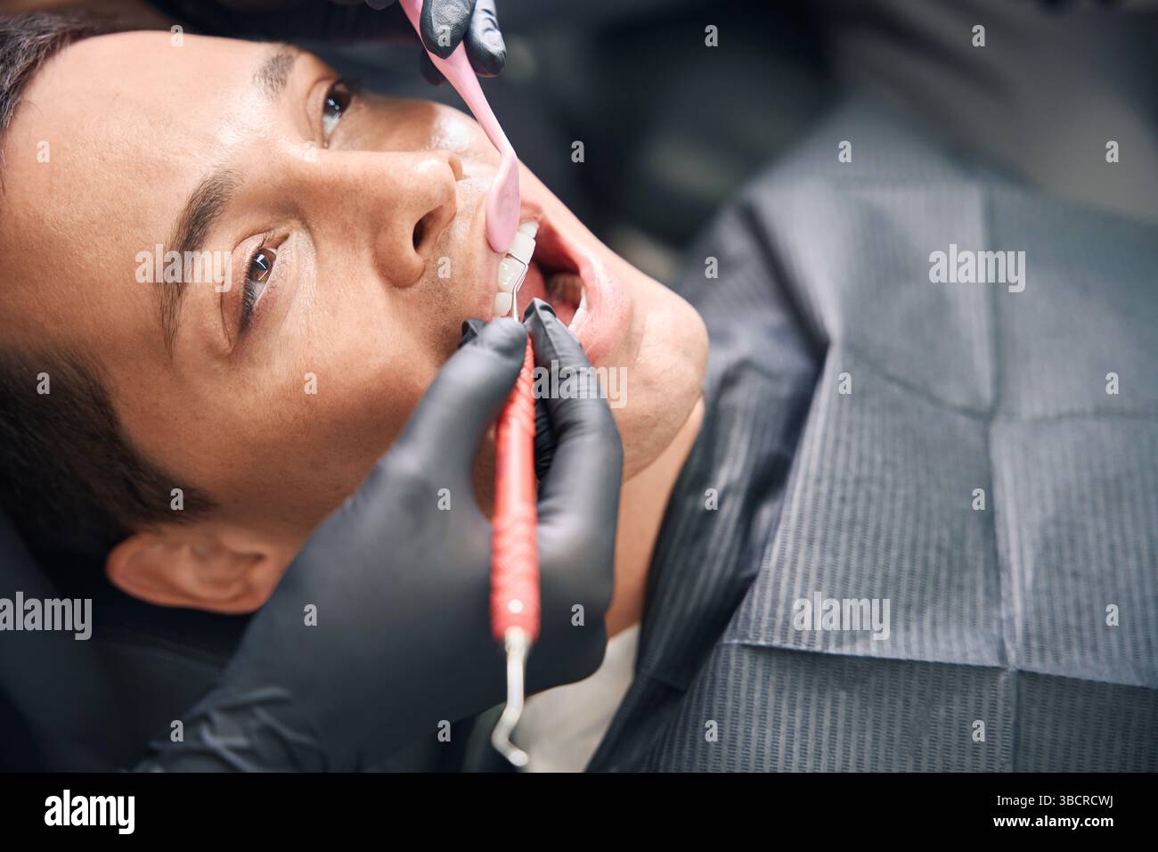 Dental professional exploring pockets between male client teeth Stock ...