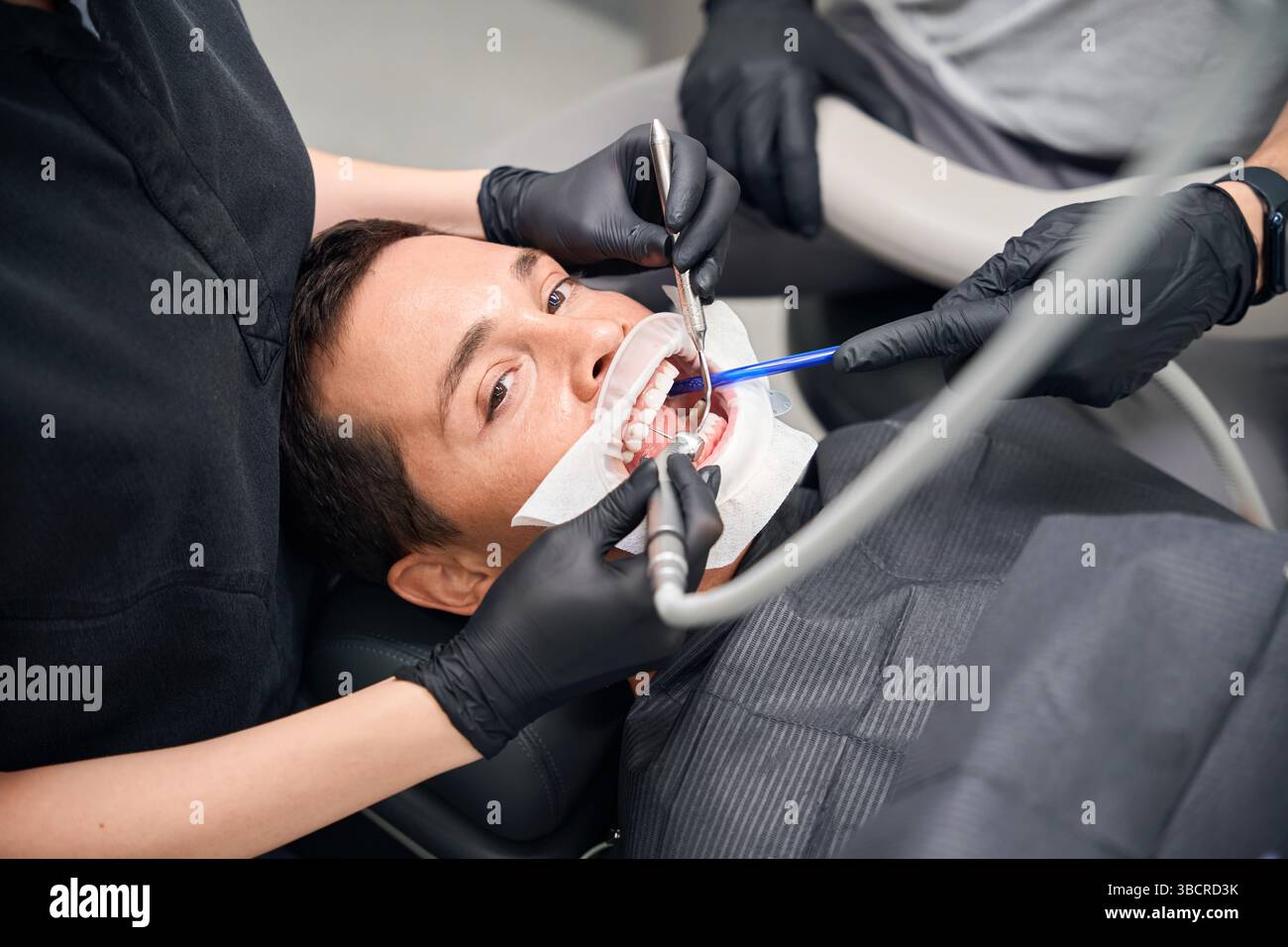 Male patient with mouth opener lying on dental chair, teeth treatment ...