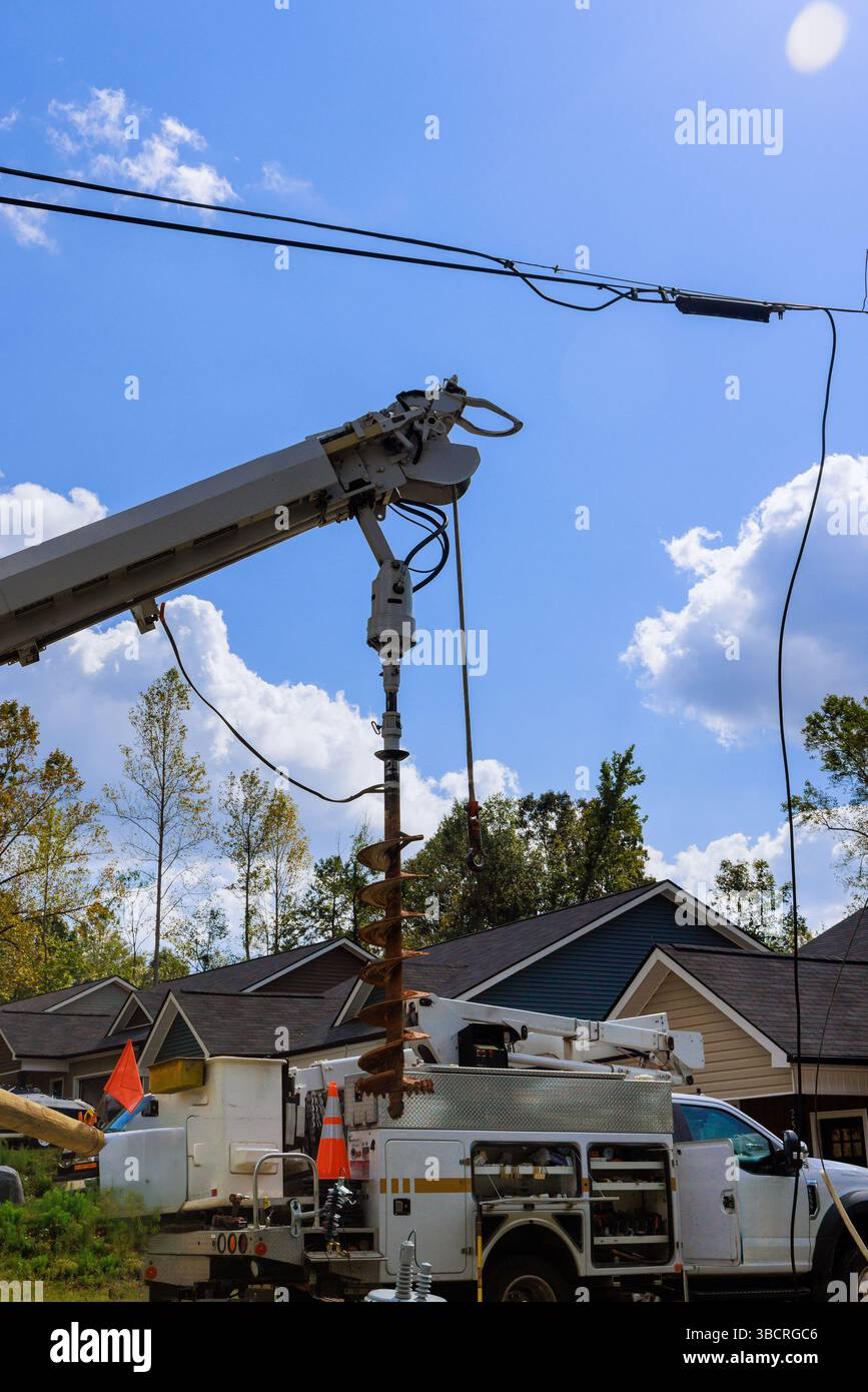 Heavy machinery is engaged in installation of utility poles surrounded ...