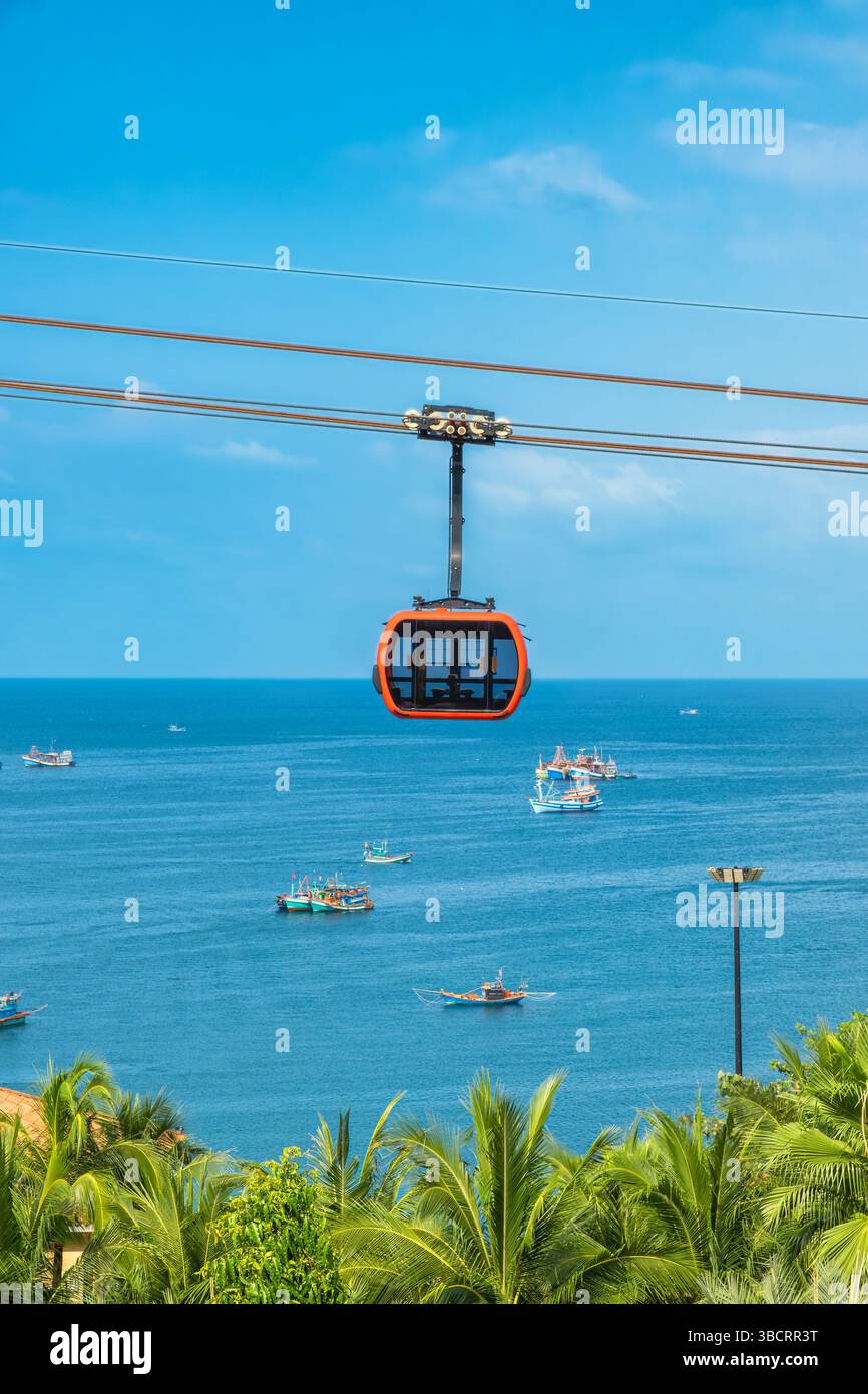 Modern cable car gondola ride over tropical seaside with fishing boats ...