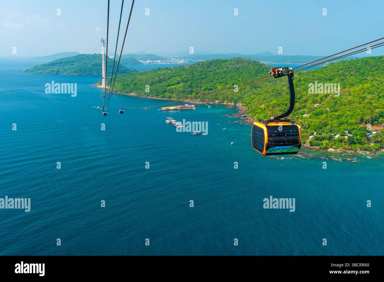 Aerial view of cable car gondola gliding over turquoise sea and green ...