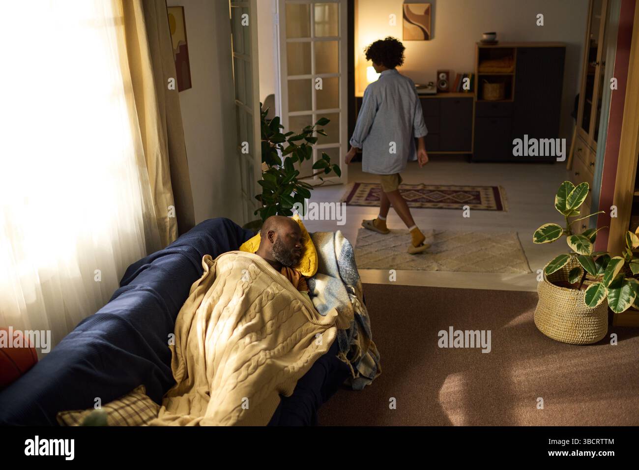 Man Sitting on a Couch While Woman Walking Away Indoors Stock Photo - Alamy