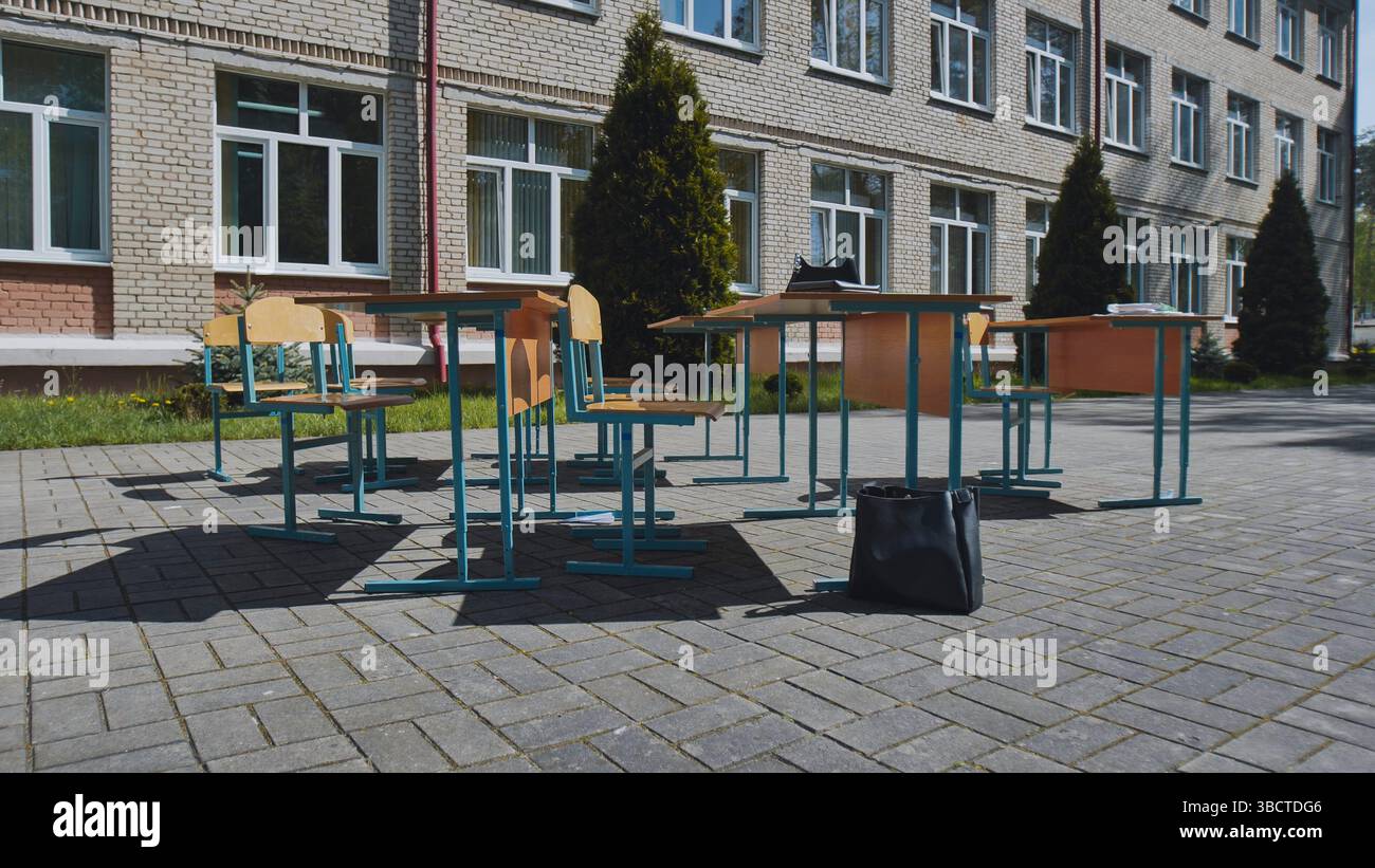 Deserted school desks and chairs lined up outside school building with ...
