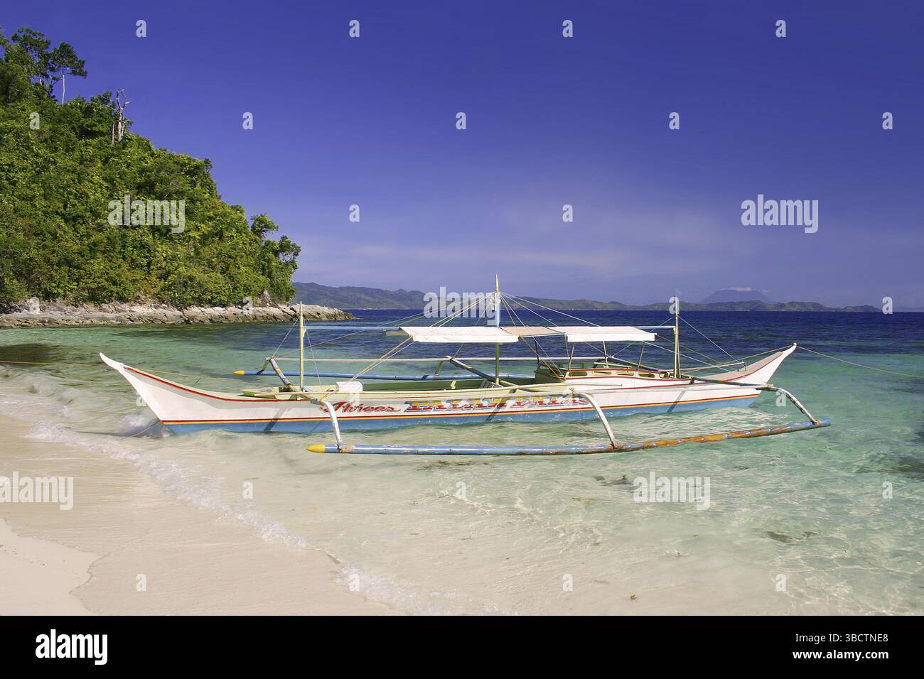 Boat tied up on beach of tropical island, blue sky and clear sea ...