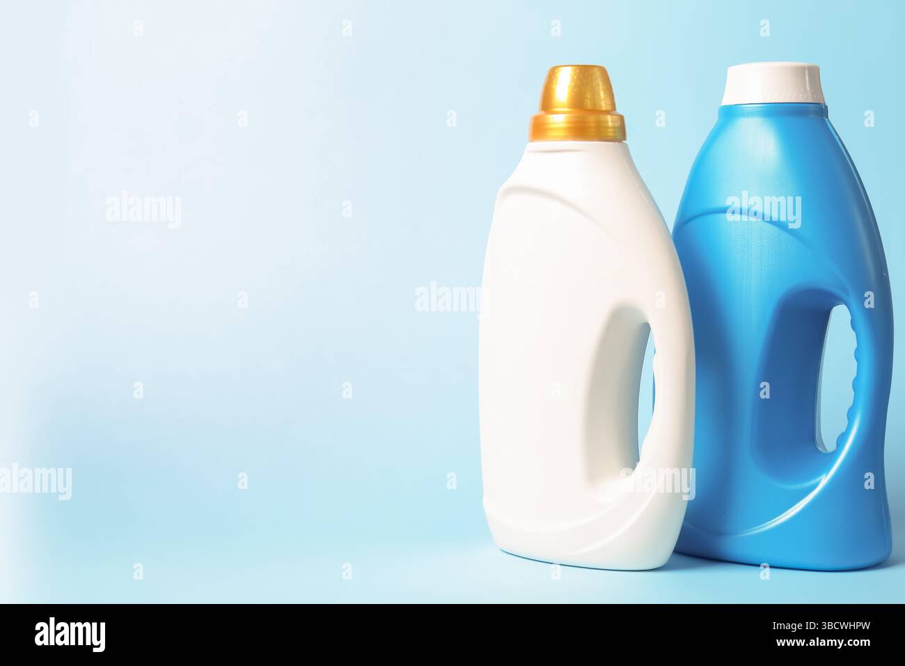 Bottles of fabric softener on light blue background, space for text ...