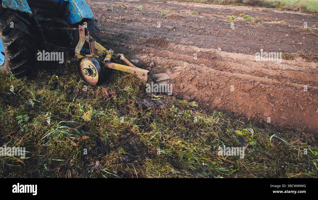Blue tractor plowing the field with a single furrow plow Stock Photo ...