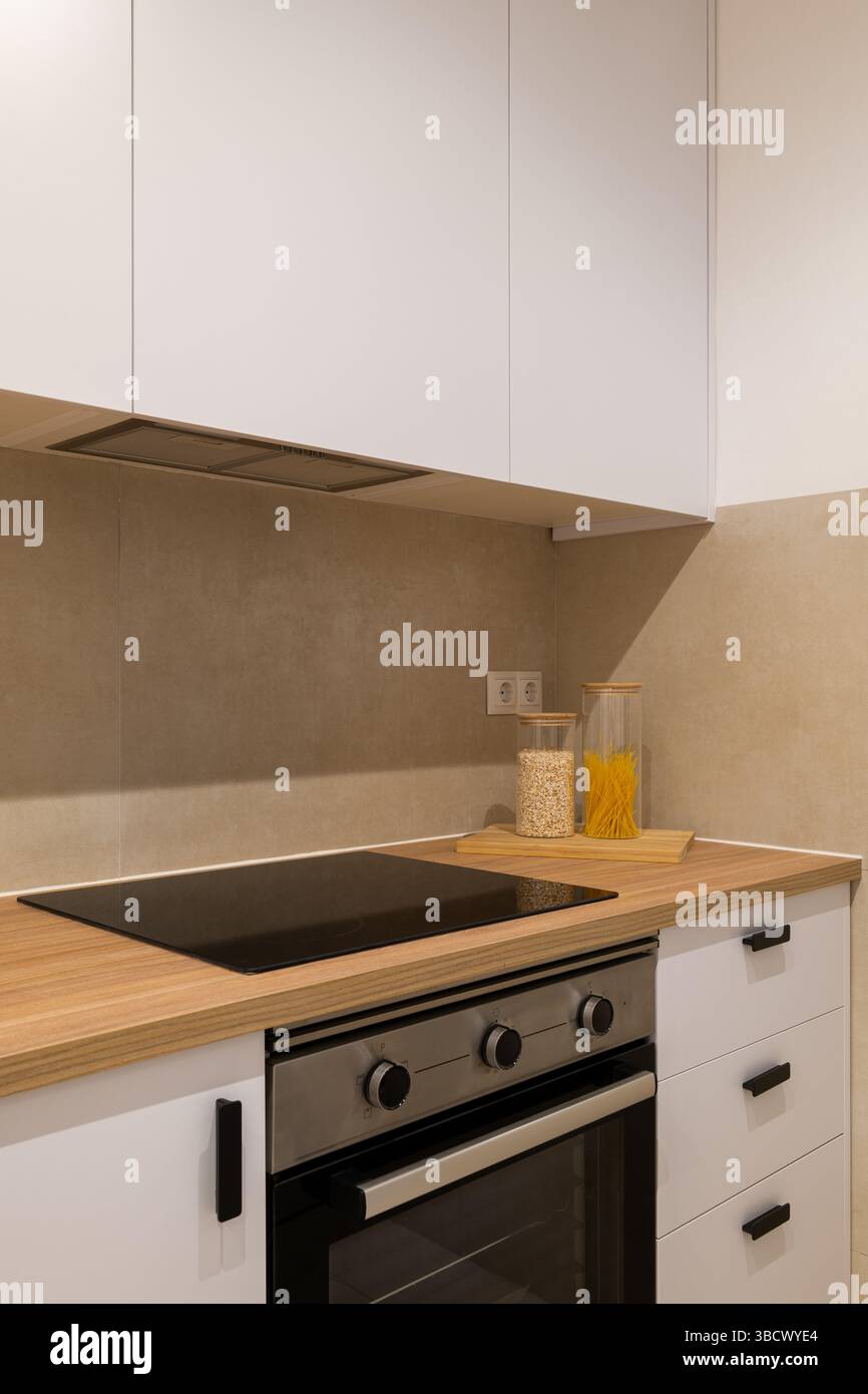 Minimalist kitchen close-up of cooktop and oven with wood countertop ...