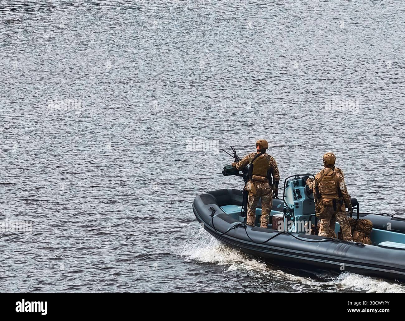 Armed soldiers on military rigid inflatable boat patrol in open water ...
