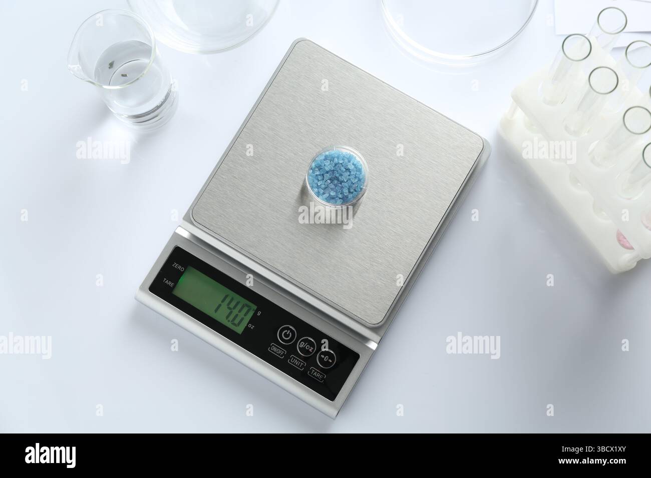 Scale with Petri dish of sample and other laboratory equipment on white ...