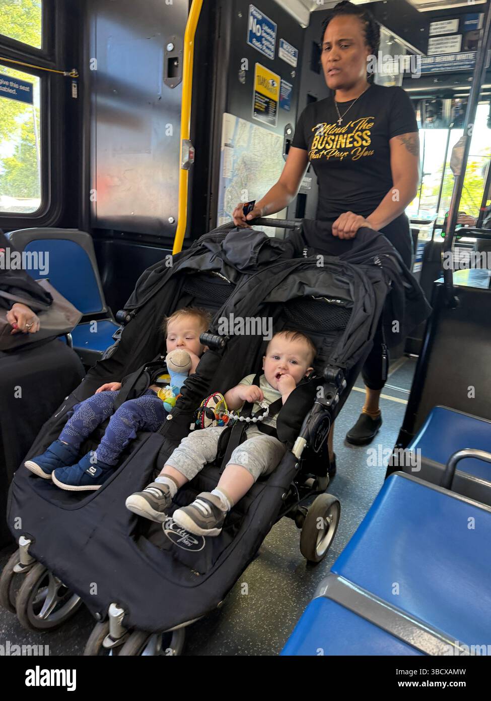 A woman (nanny) pushing a duble stroller with twins onto an MTA bus in ...