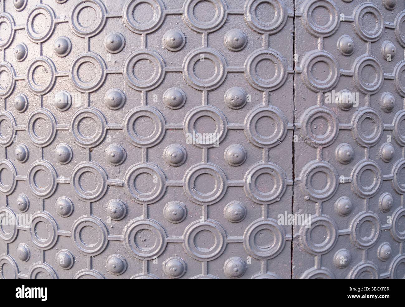 A close-up view of a textured surface featuring circular patterns and raised dots, painted in a ...