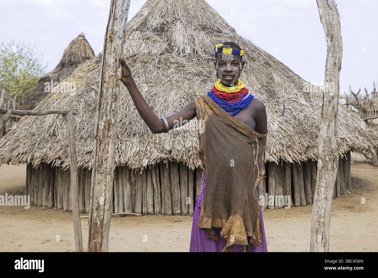 Black woman with painted face of the Karo, Kara tribe in front of hut ...