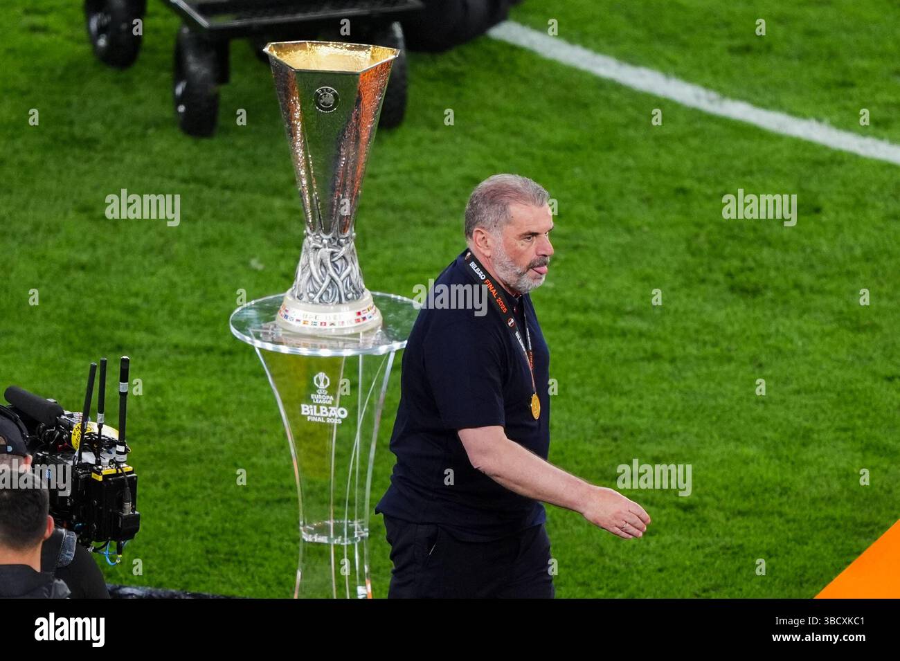 Tottenham Hotspur manager Ange Postecoglou walks past the trophy as he ...