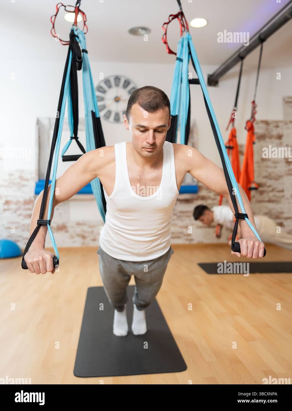 Man performing chest press with TRX straps during Pilates training ...