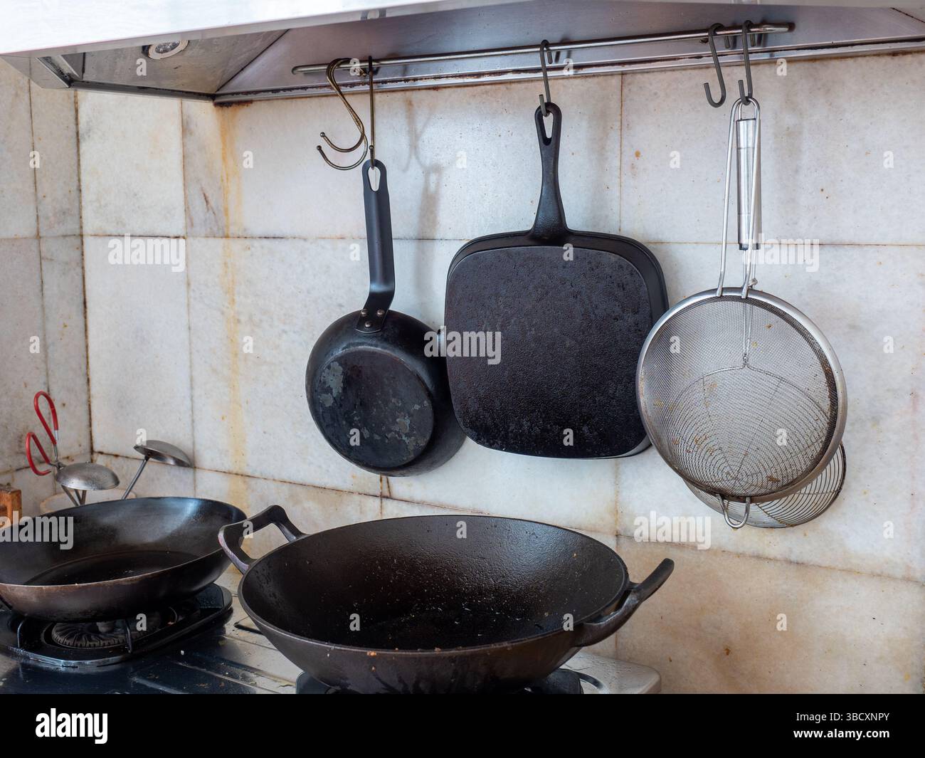 A view of a gas stove area with skillet, pan, wok and strainer cooking ...