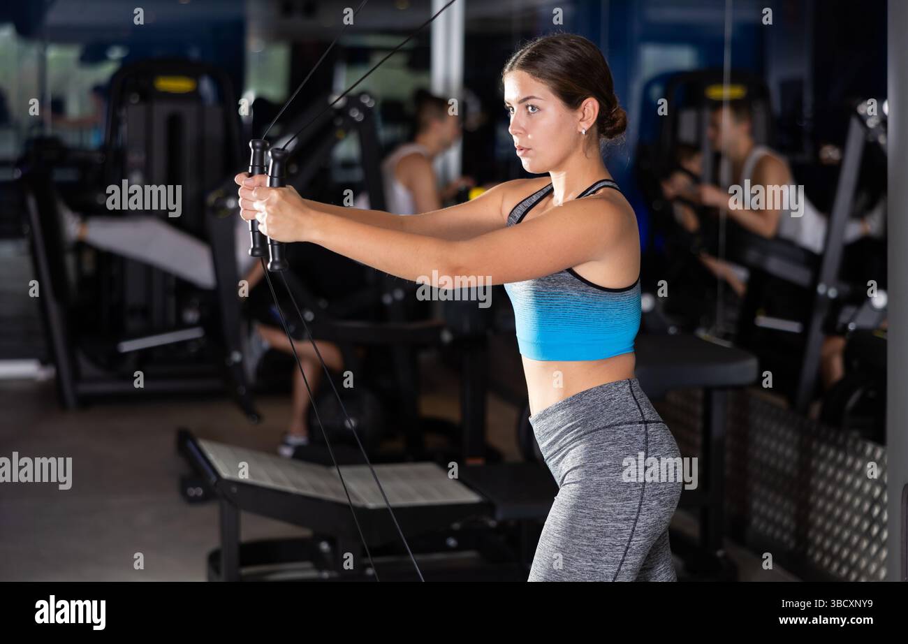 Active athlete young woman during exercises on crossover exercise ...