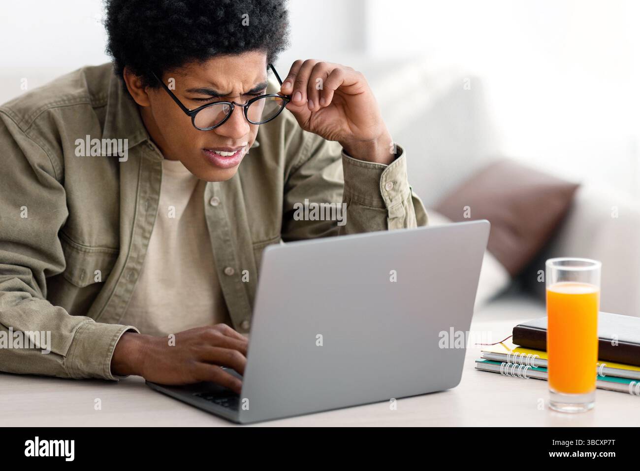 Poor eyesight. Black teenager in glasses squinting his eyes while using ...