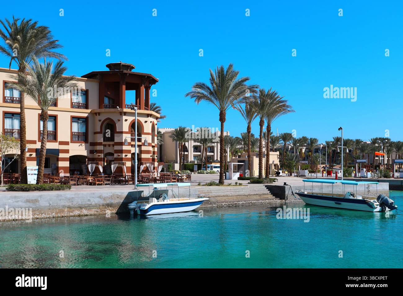 Colorful waterfront promenade with palm trees and striped buildings in ...