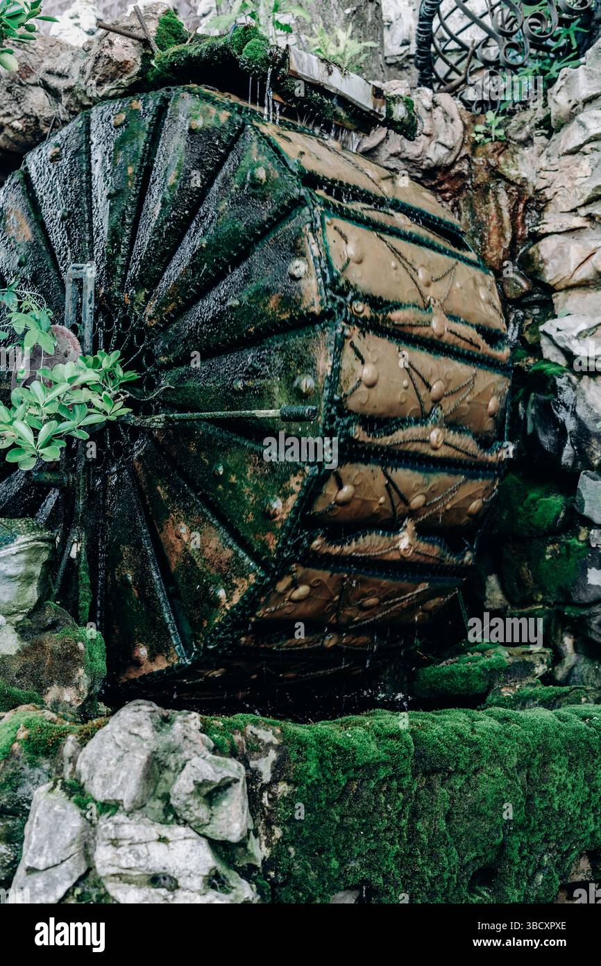 Old mossy water wheel turning in stone fountain ancient mechanism in ...
