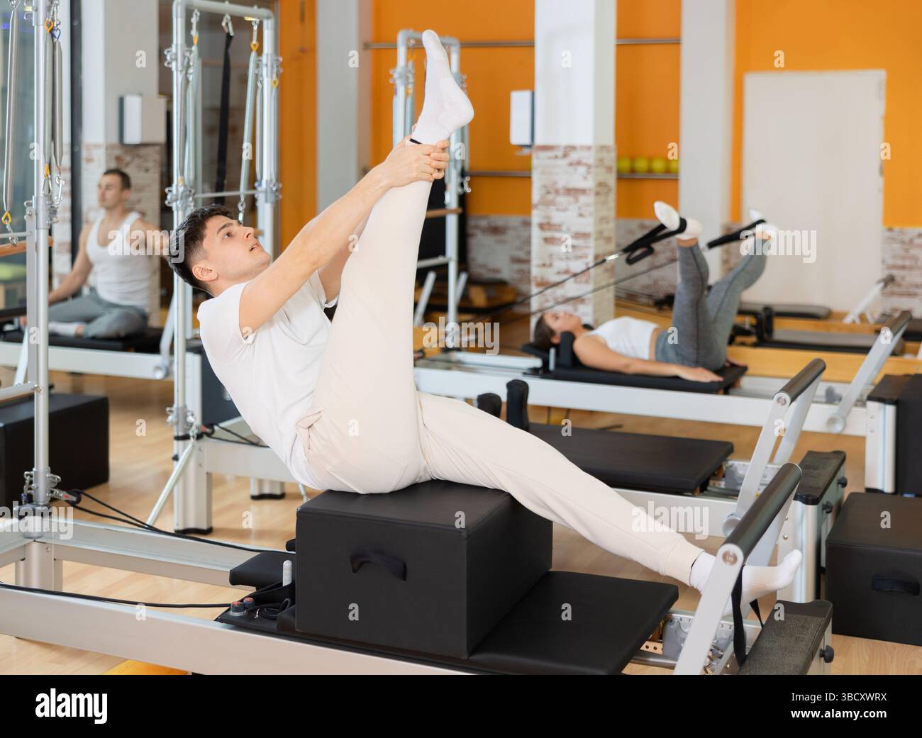 Man works out in gym and performs set of exercises to stretch leg ...