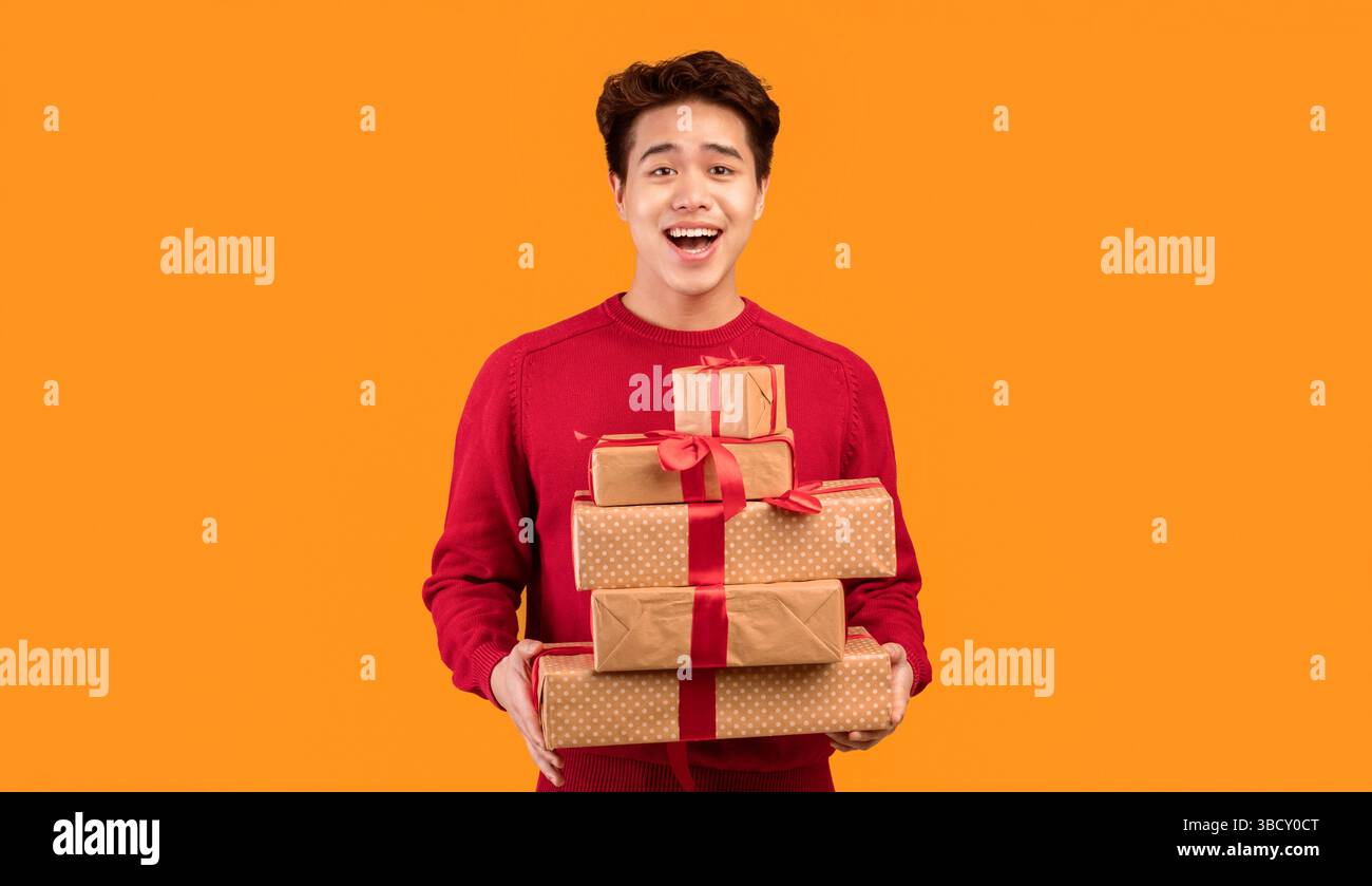 Happy asian guy holding stack of present boxes Stock Photo - Alamy