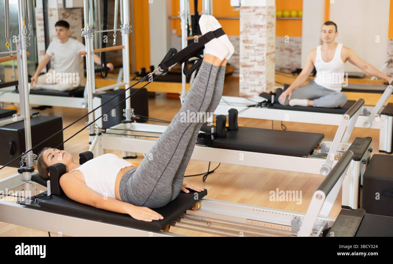 Girl doing exercises with feet in straps on Pilates reformer Stock ...
