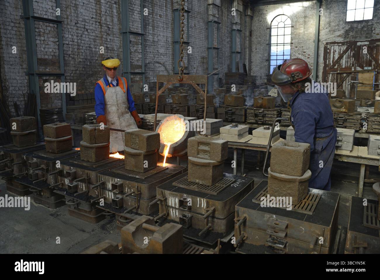 Foundrymen pour molten iron into moulds for making fire grates Stock ...