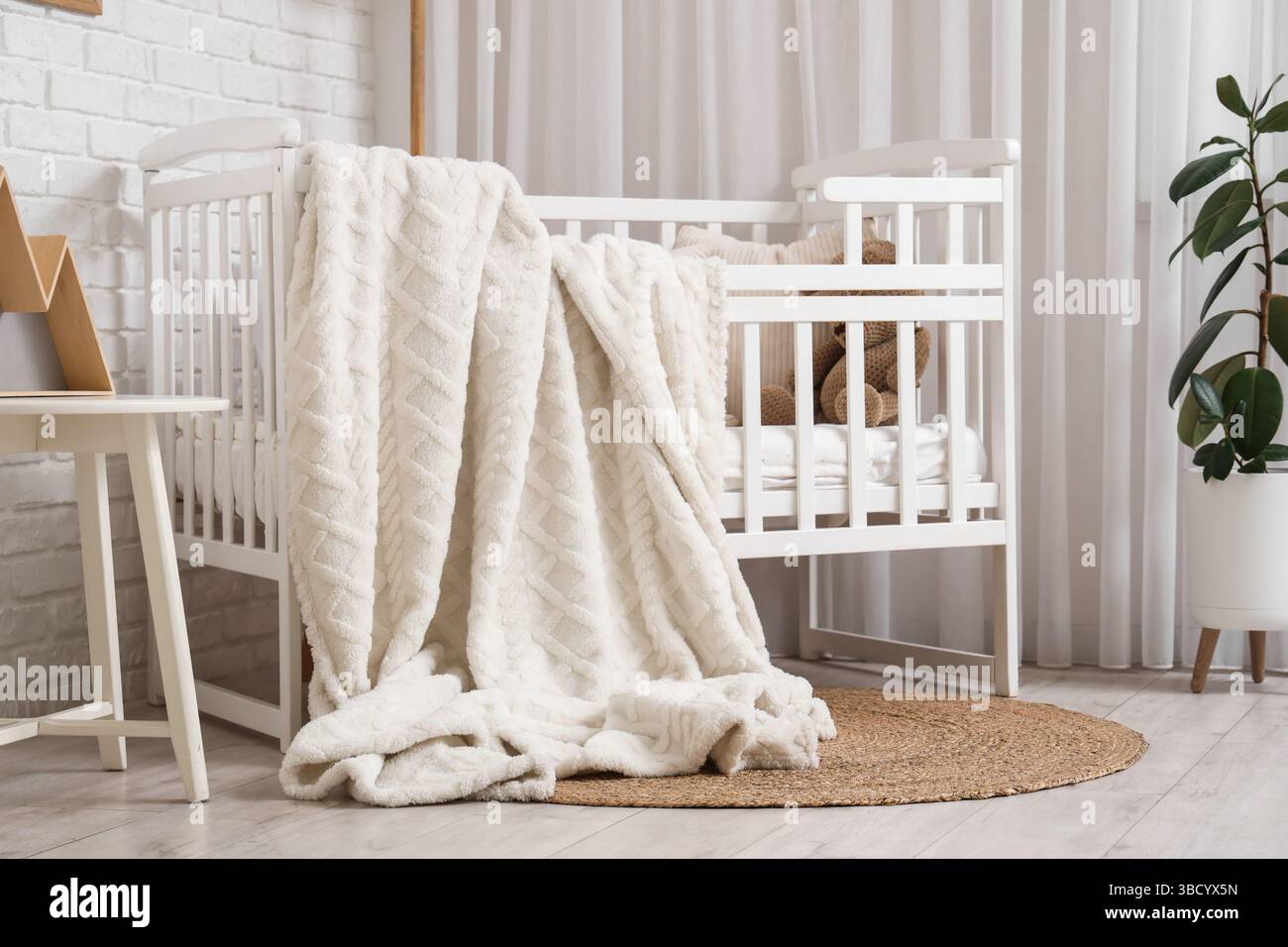 Beautiful crib with plaid near white brick wall in interior of children ...