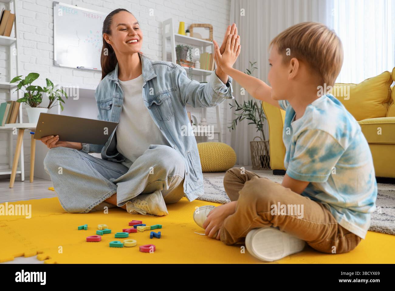 Female speech therapist with little boy giving each other high-five in ...