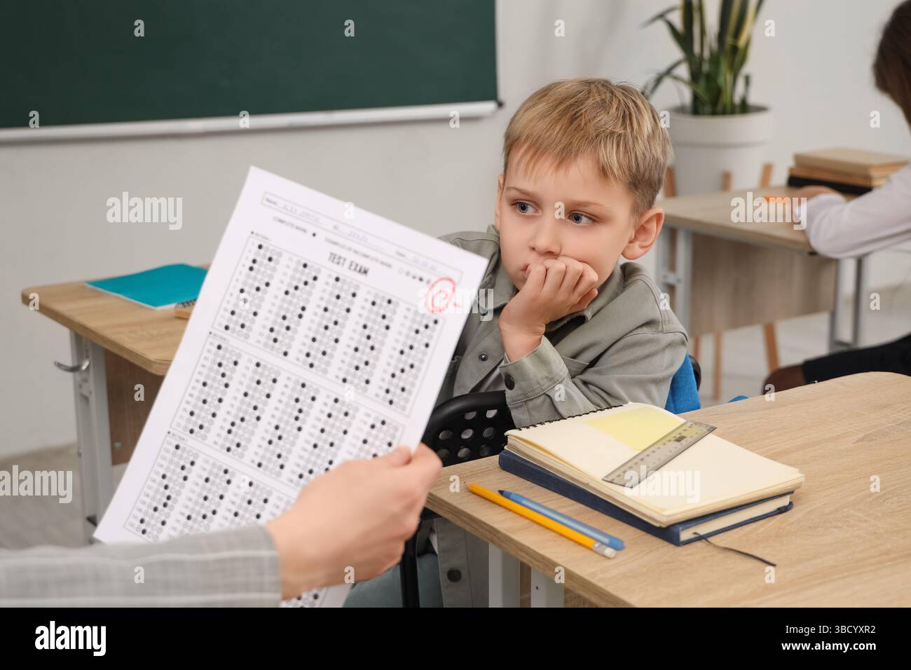 Worried schoolboy receiving answer sheet with C grade from teacher in ...