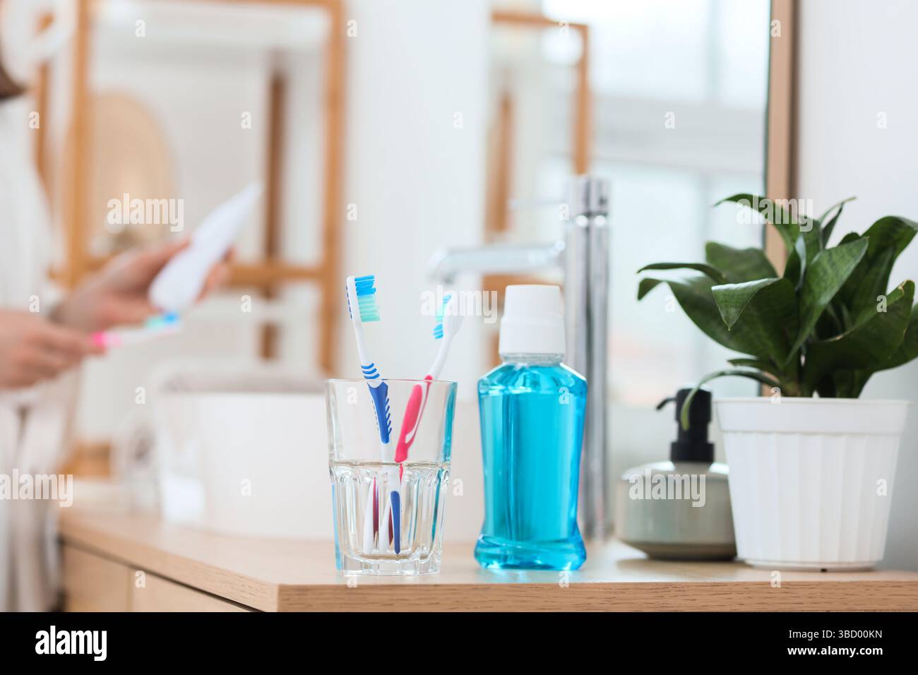 Glass with tooth brushes and mouth rinse on table in bathroom Stock ...