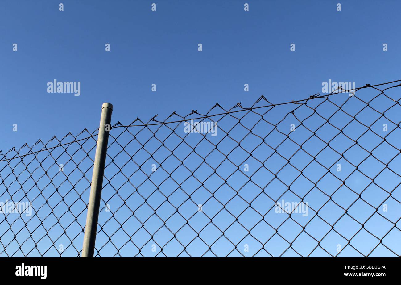 Section of old chain-link fence against a bright blue sky Stock Photo ...
