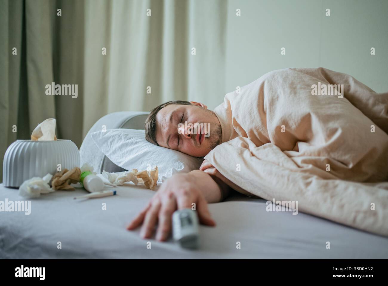 Sick man sleeping in bed, wrapped in a cozy blanket, holding a ...