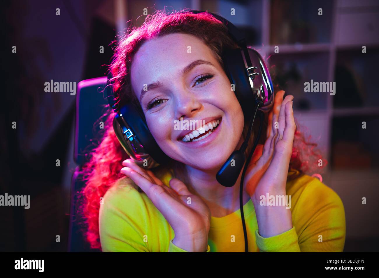 Cheerful female gamer enjoying an online livestream session with neon ...