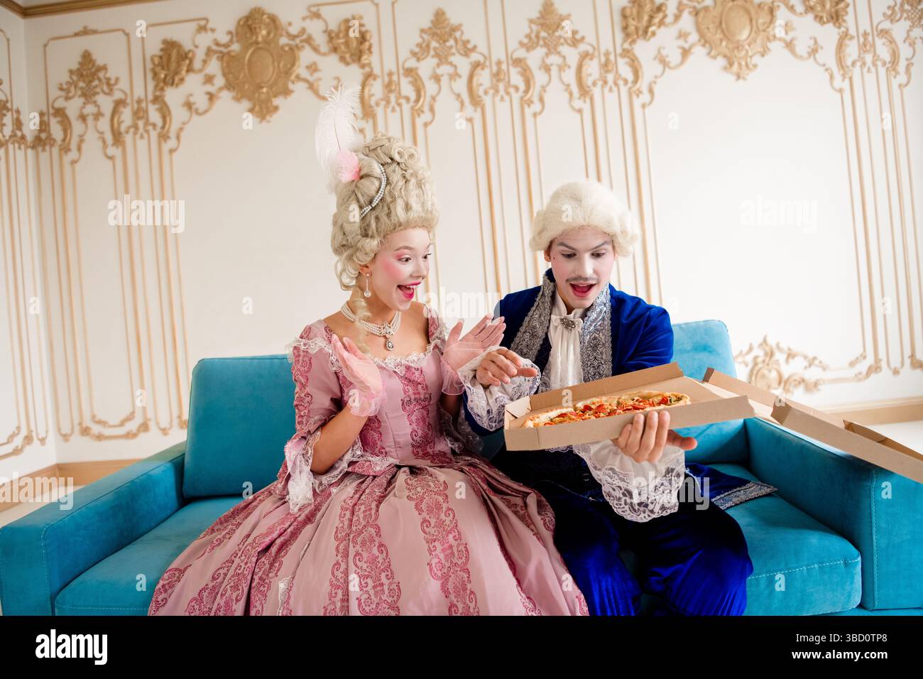 Elegant couple in baroque costumes enjoying pizza in a vintage palace ...