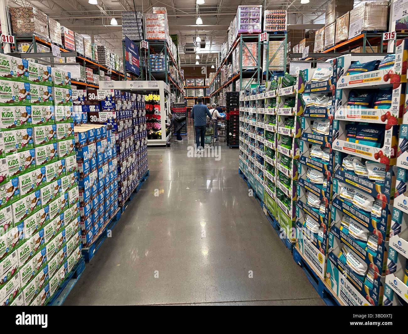 Shoppers push their carts amid long rows of items on display in a ...