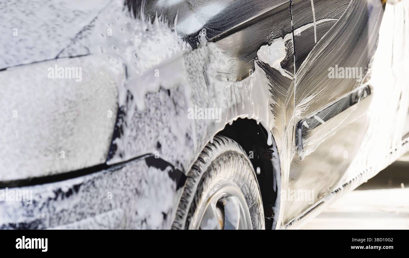 Car wash with active foam dripping on black car Stock Photo - Alamy