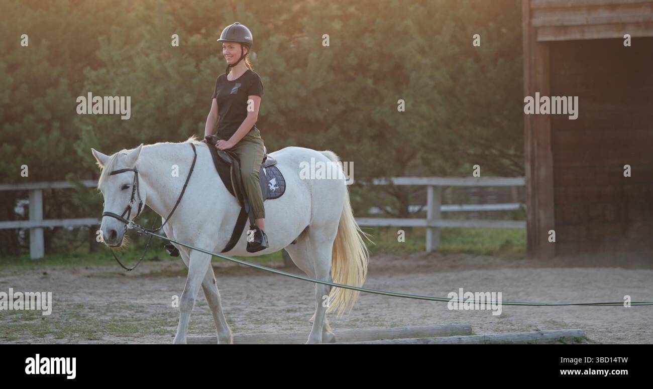 Horseback riding training, young jockey riding white horse in paddock ...