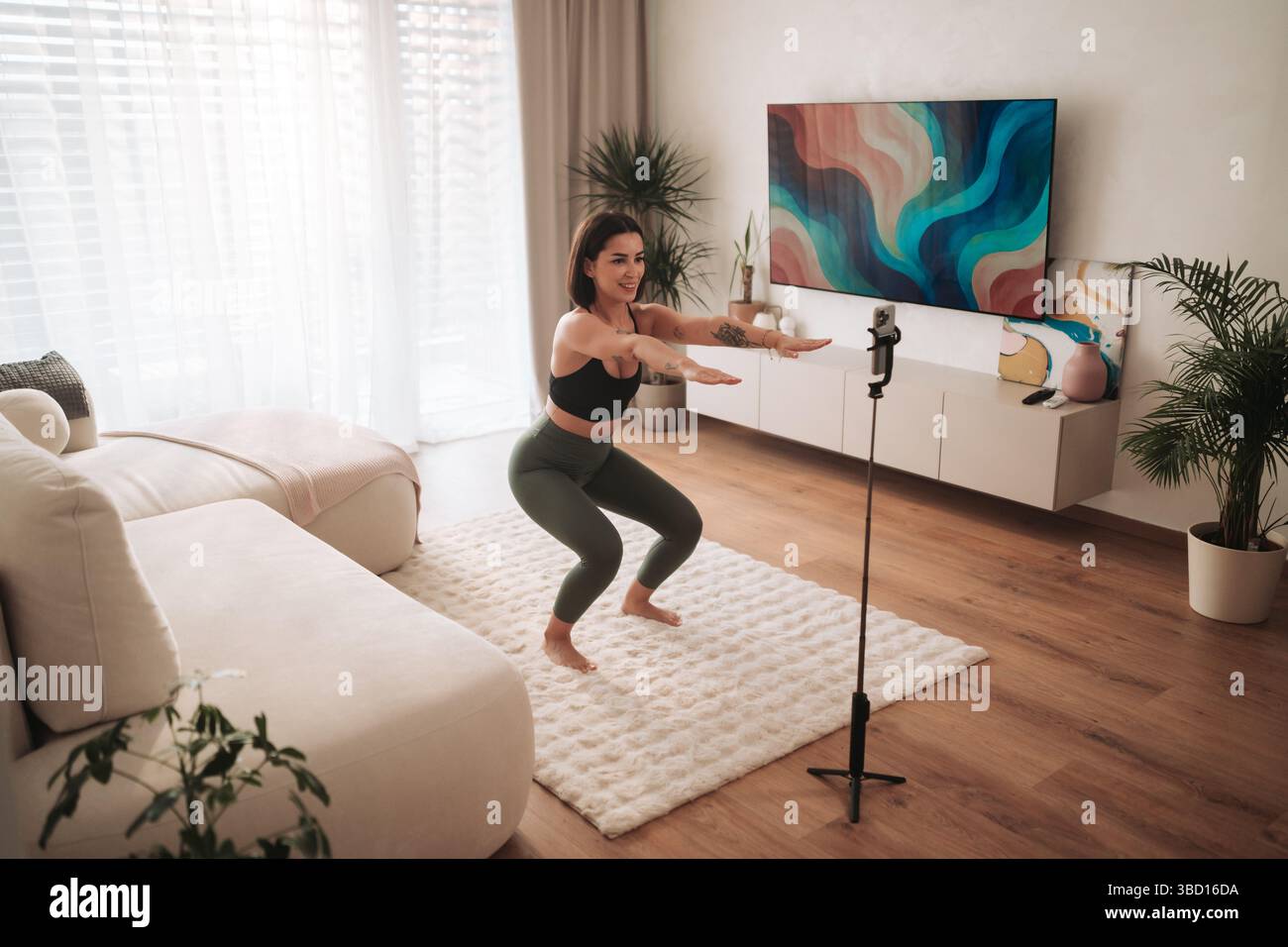 A Young Woman Engaging in Squats at Her Home Gym, Equipped with a Live ...