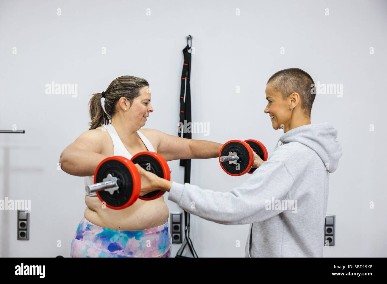 Personal trainer helping client with shoulder and back training using ...