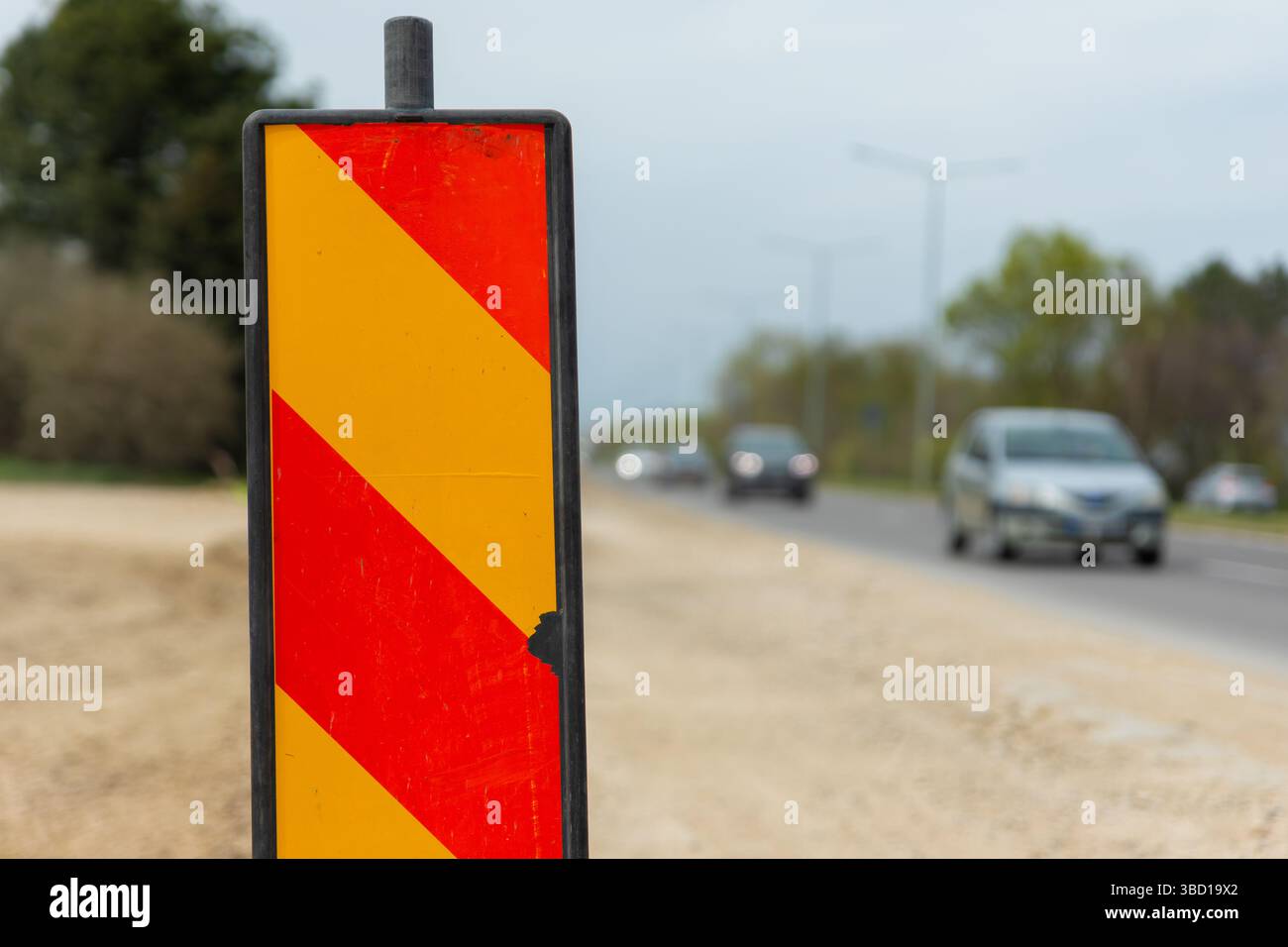 Diagonal red and yellow striped warning sign at a roadside construction ...