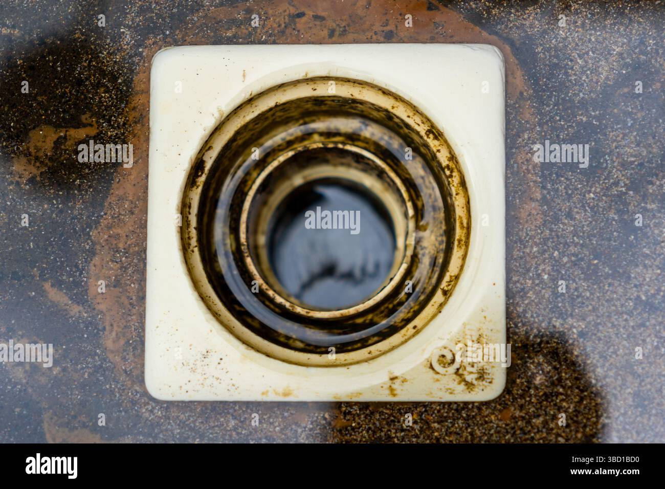 Dirty drain with a white cap. The drain is full of water and has a ...