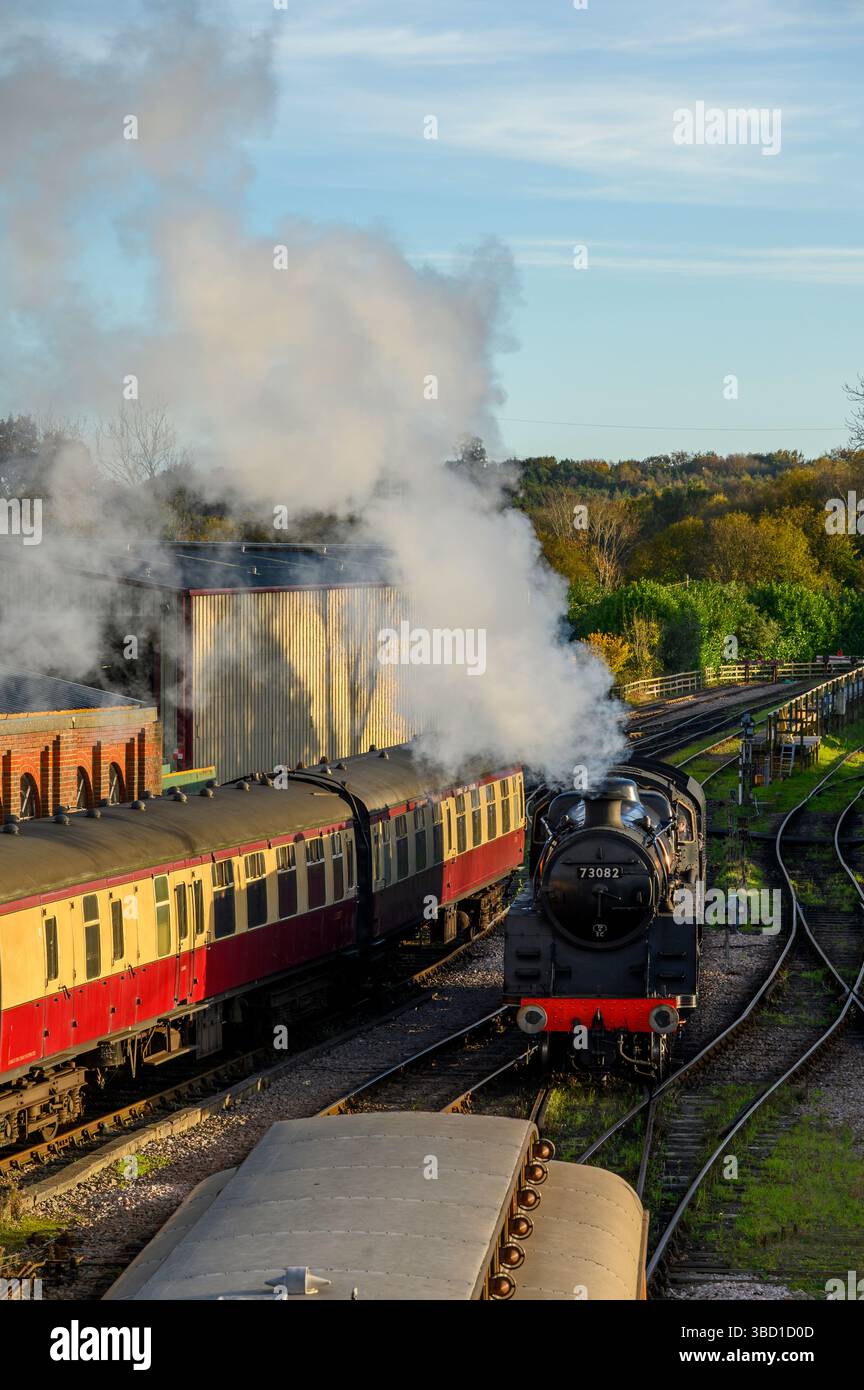 A steam locomotive shunts passenger carriages on Bluebell Railway Line ...