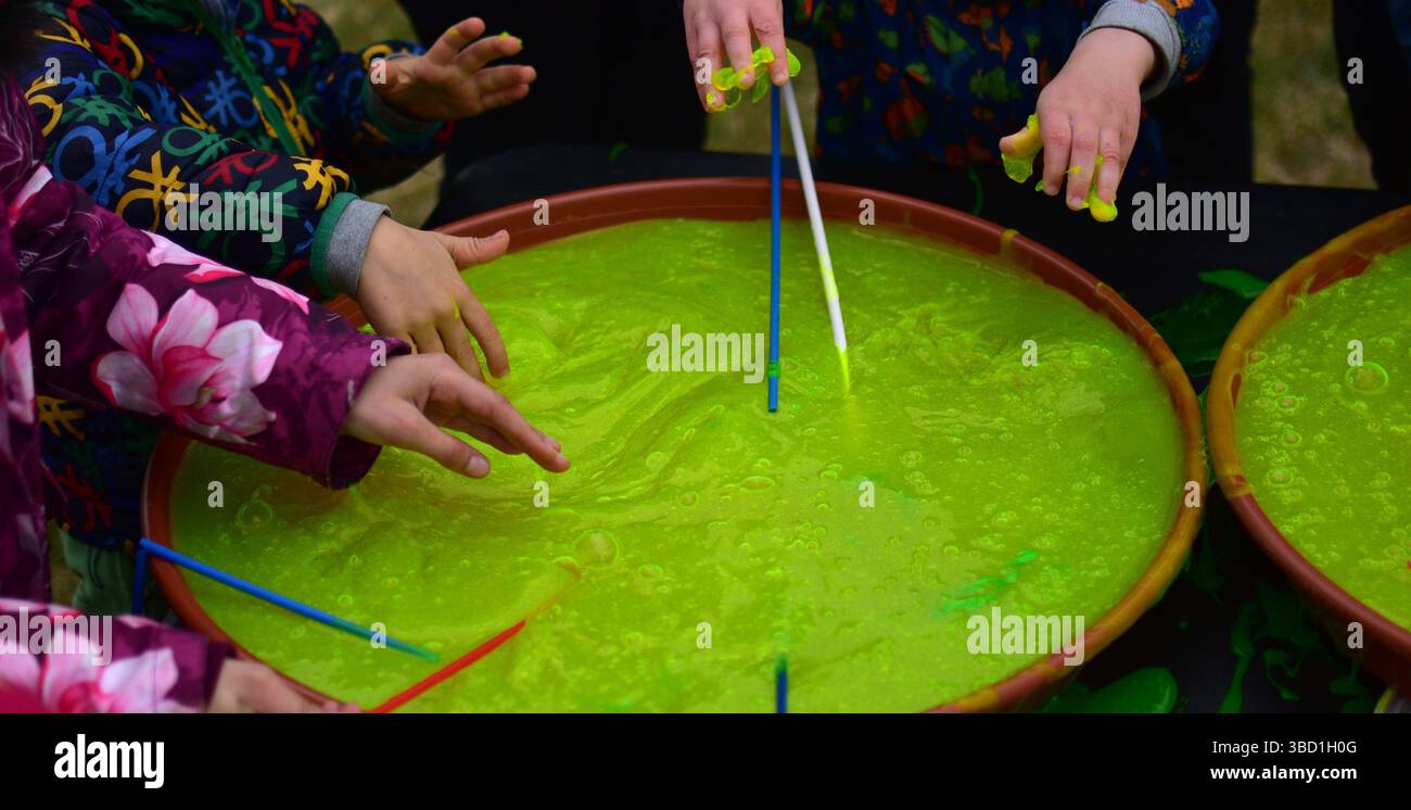 Children hands closeup playing with neon green slime in a large sensory ...