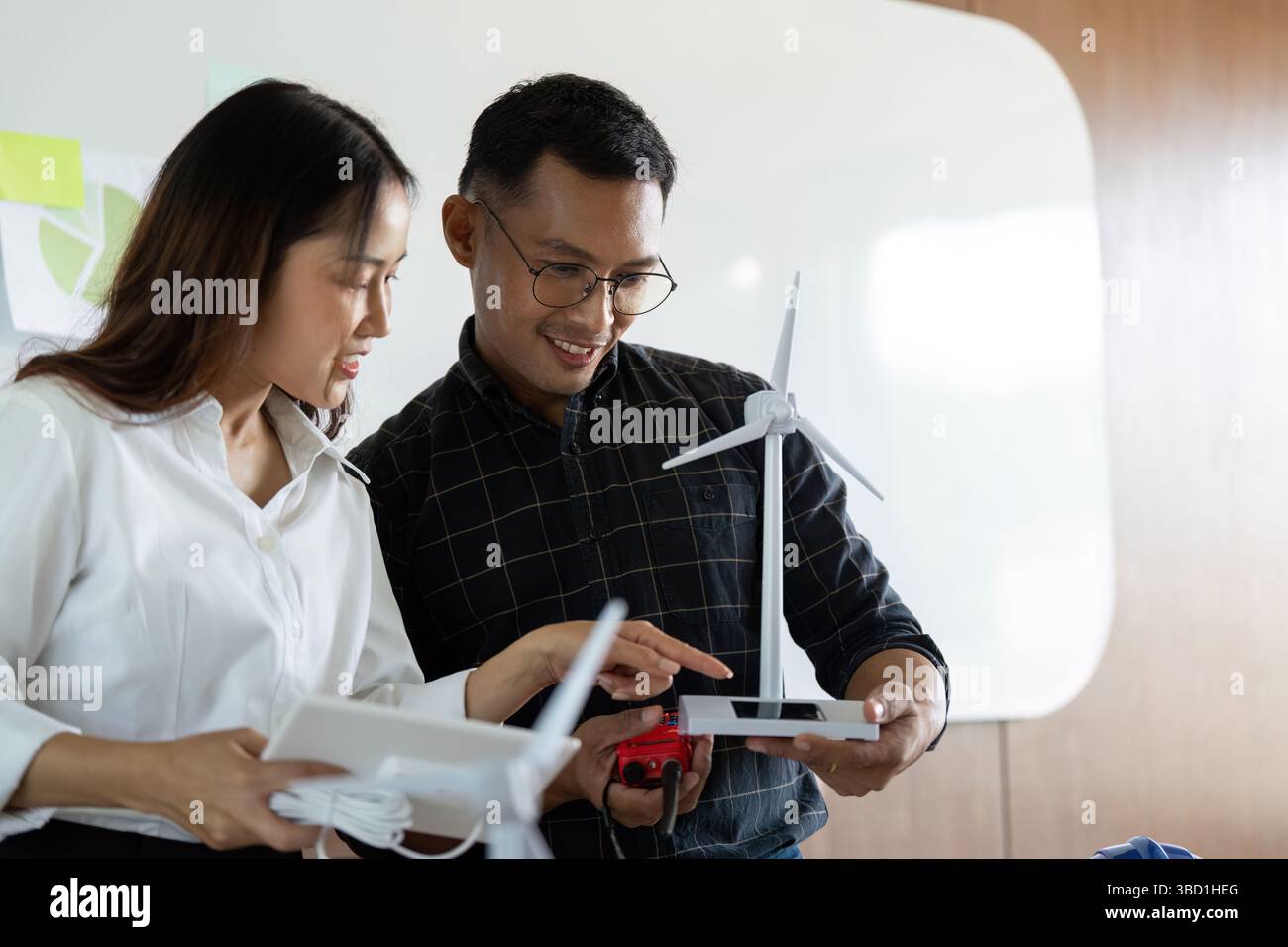 Sustainability and Engineering. Engineers collaborating on wind energy models in a modern office ...