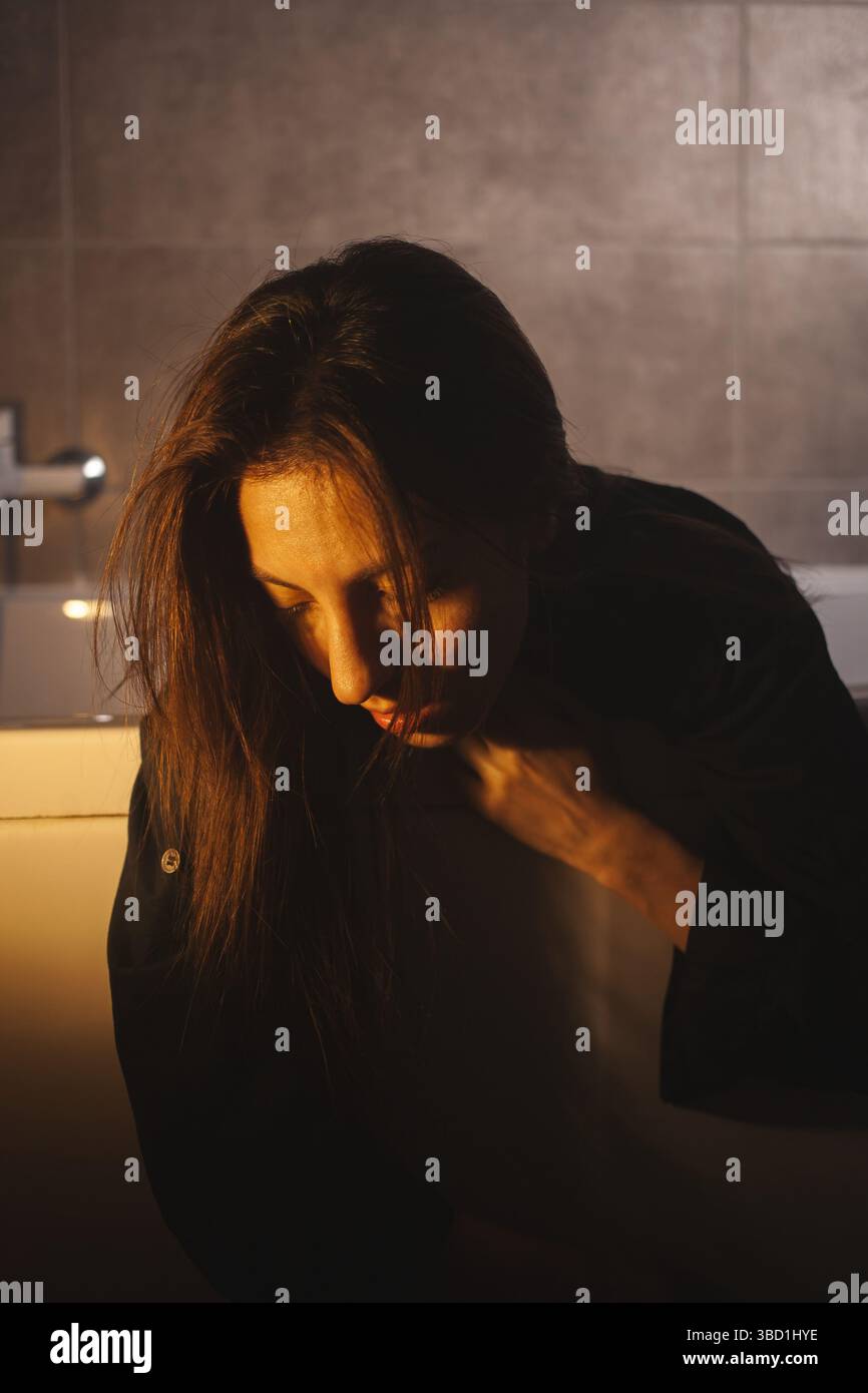 Lonely woman sitting slumped in bathtub, fully clothed Stock Photo - Alamy