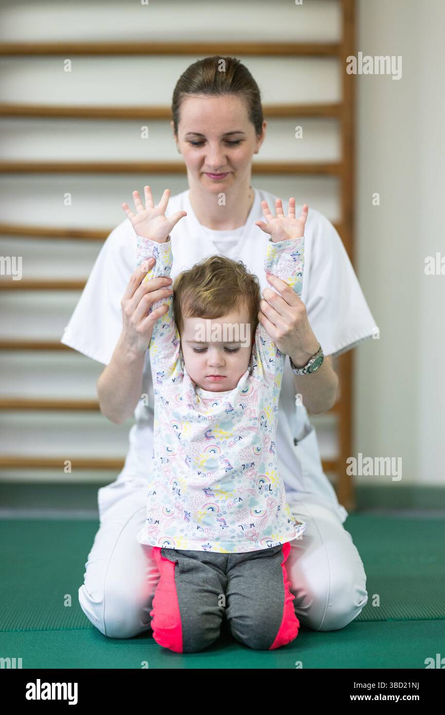 Pediatric Physiotherapy Session.Female physiotherapist helping a young ...