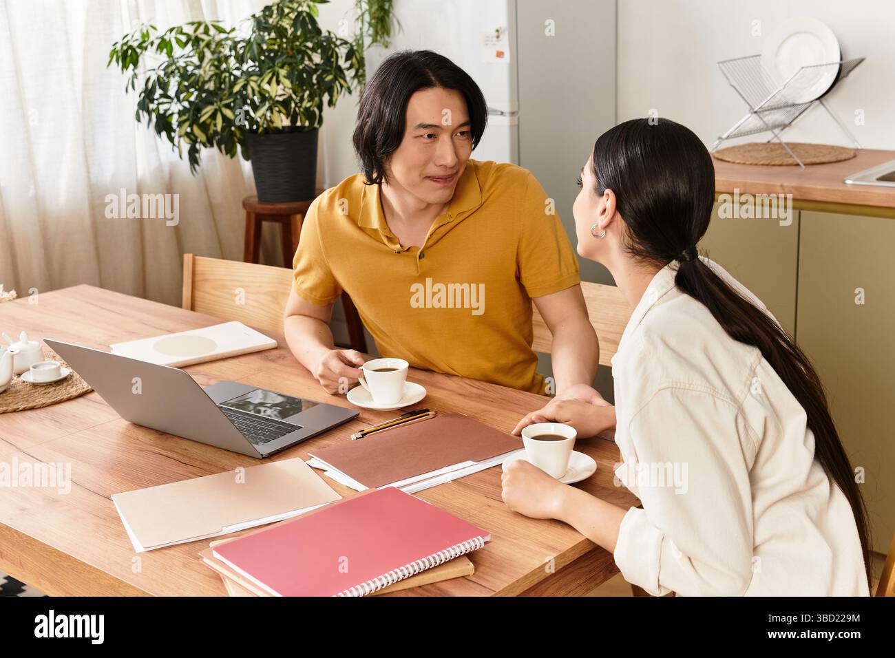 A couple shares coffee at home, smiling and engaging in warm ...