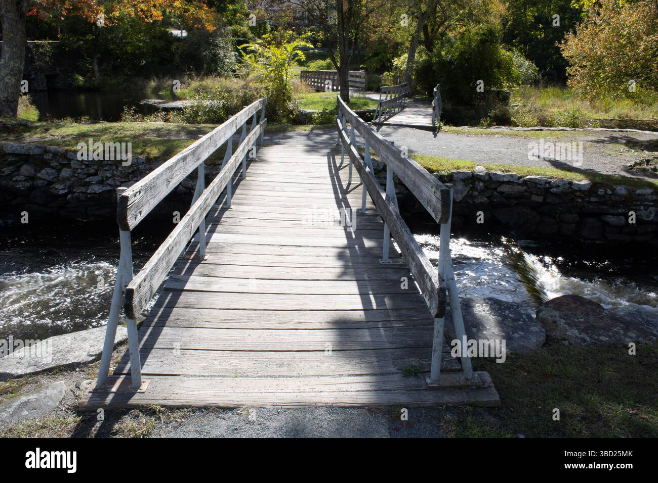 Autumn's breathtaking display: a footbridge spans flowing water ...